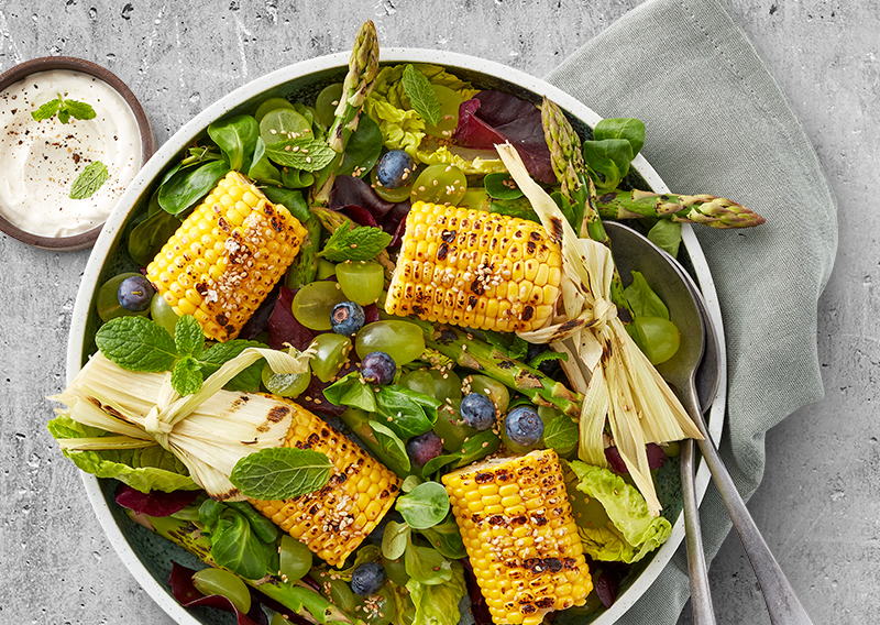 Frisk salat med grønne asparges, blåbær, grillet majs og grønne druer ...